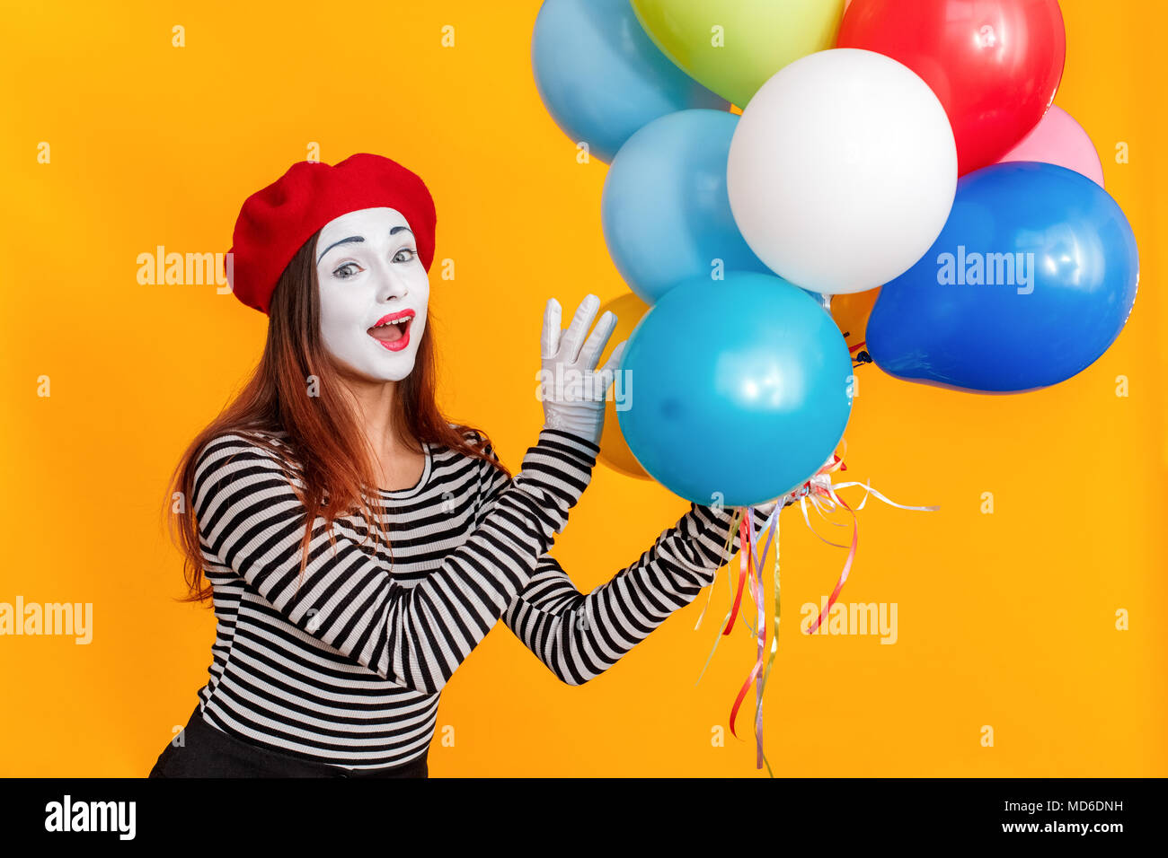 Portrait of cute mime woman holding many colorful air balloon. Emotions ...