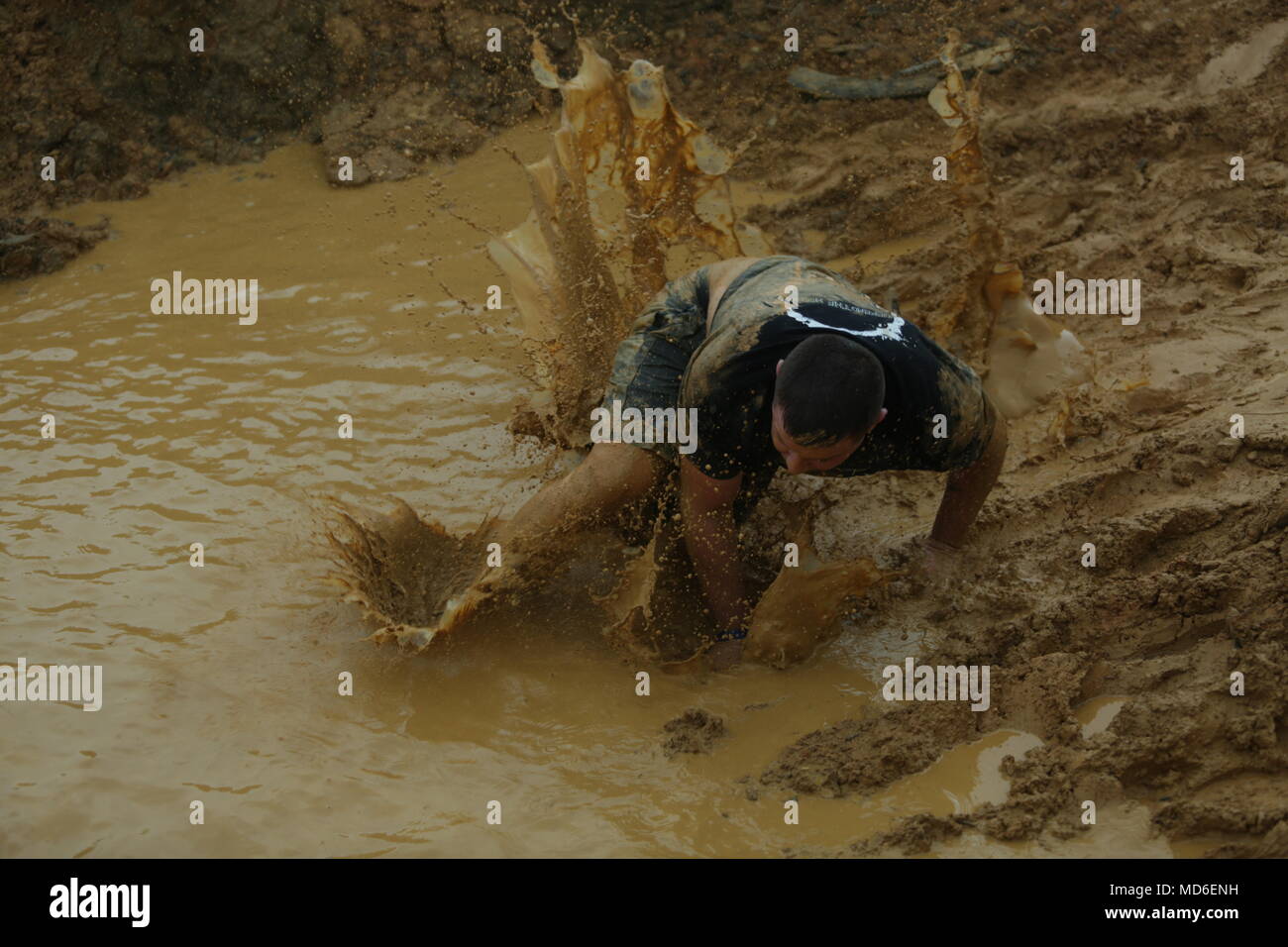 CAMP HANSEN, OKINAWA, Japan – A runner slides down into a pool of murky ...
