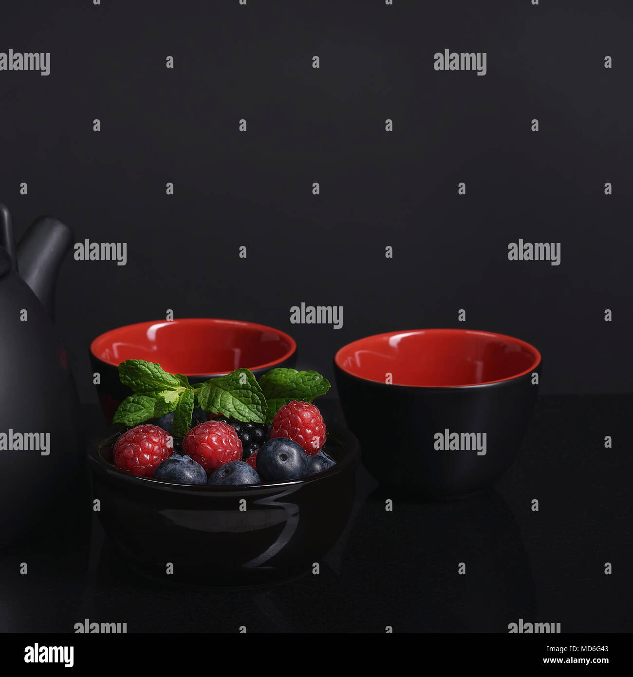 Items for tea on the table, black and red cups with black-red berries ...