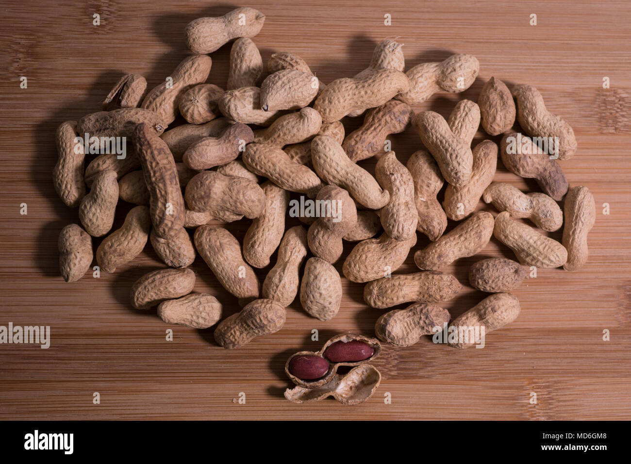 Pile of unshelled natural peanuts in the shell on a natural wooden ...