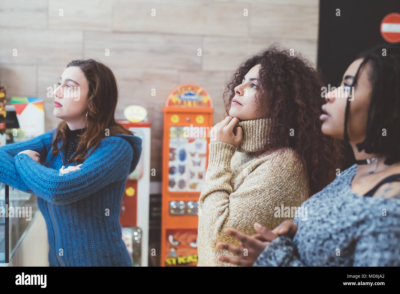 three young women multiethnic indoor staring at something - ordering ...