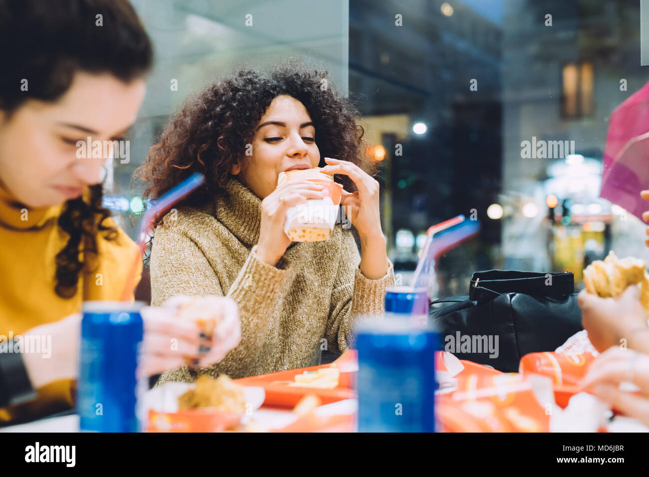 two young women multiethnic indoor eating at fast food - food and drink ...