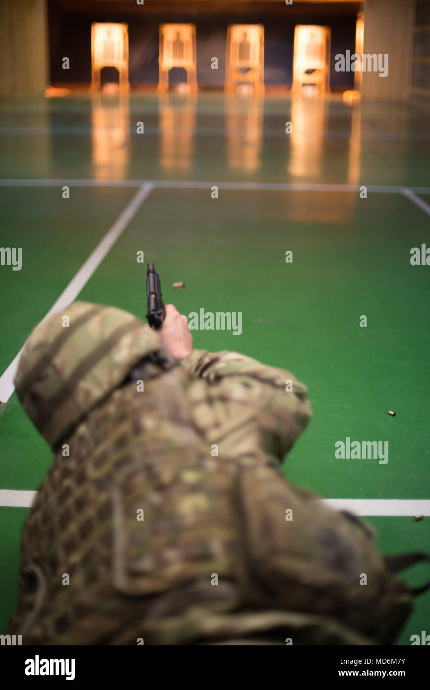 A member of the U.K. forces shoots with an M9 pistol in the prone ...