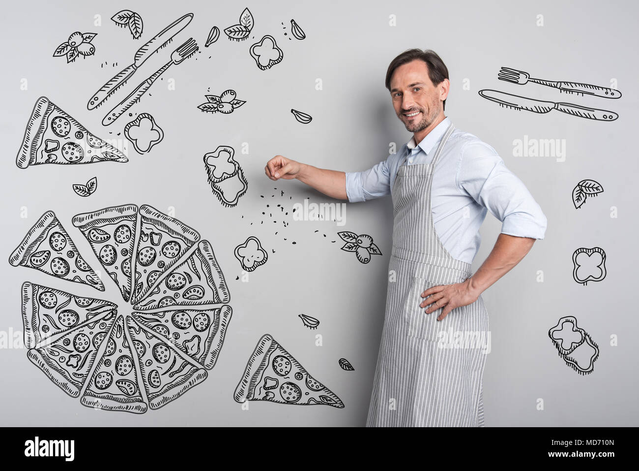 Smiling cook adding spices while cooking pizza Stock Photo - Alamy