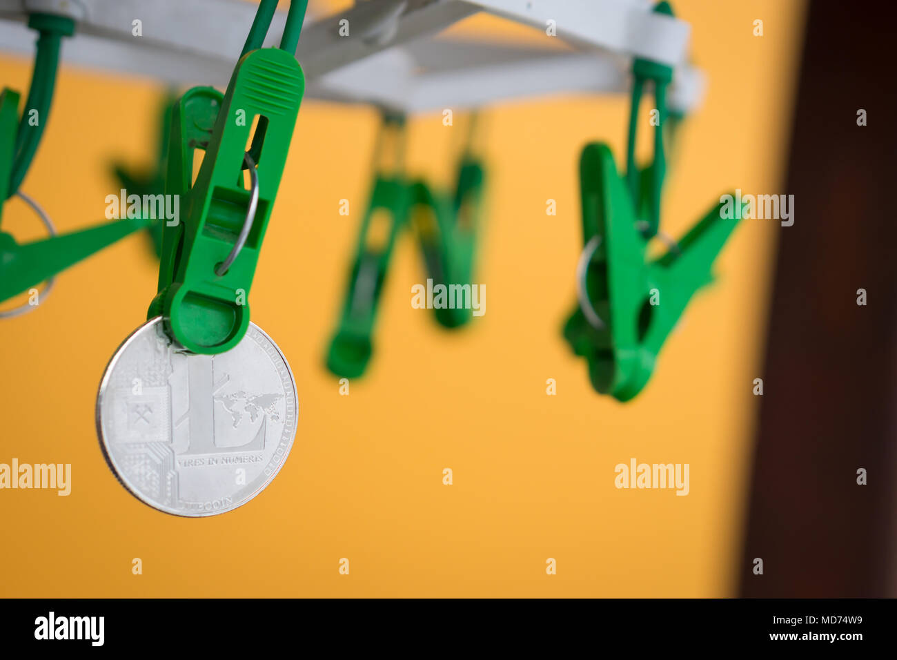 Green clothes peg hold one silver Litecoin Stock Photo - Alamy