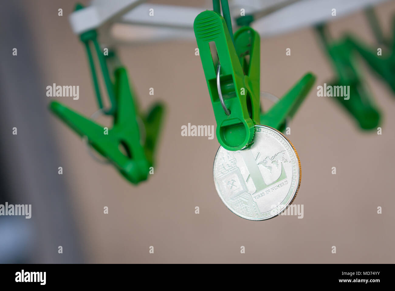 Green clothes peg hold one silver Litecoin Stock Photo - Alamy