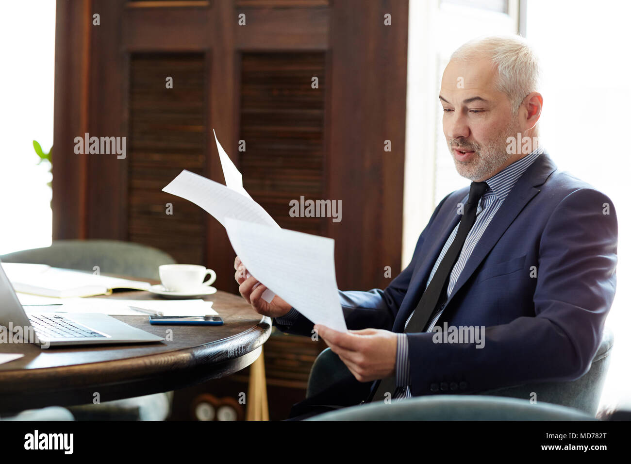 Middle-aged Caucasian manager in formal attire sitting at table with ...