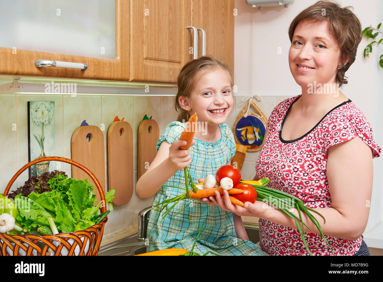 Mother and daughter cooking. Basket of vegetables and fresh fruits in ...