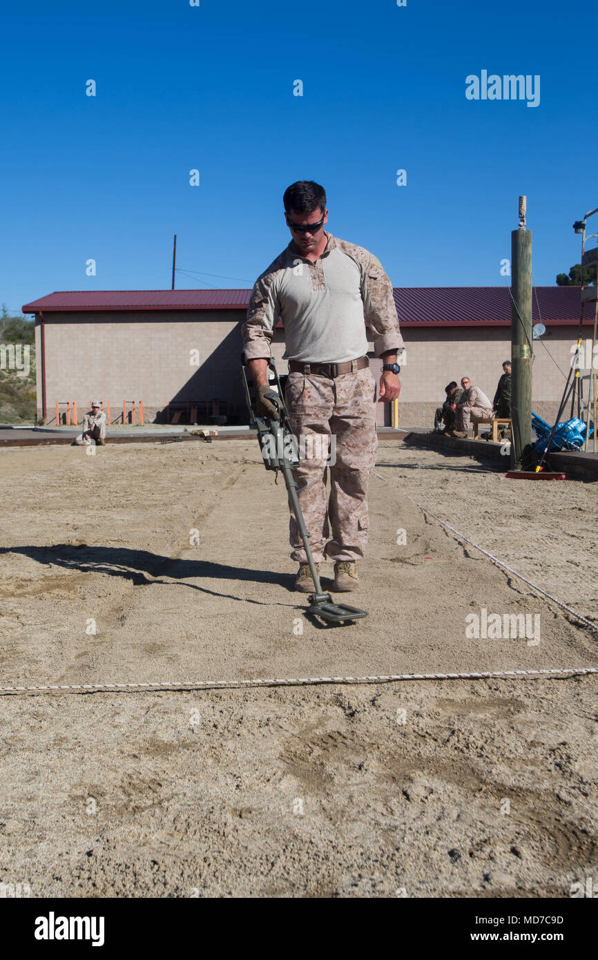 A U.S. Marine uses a compact metal detector on an improvised explosive ...