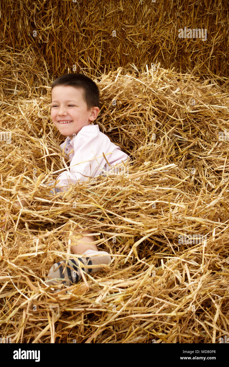 Boy lying and playing on haystack Stock Photo - Alamy
