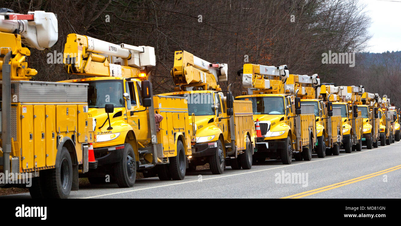 A convoy of yellow electric utility trucks in formation heading south ...