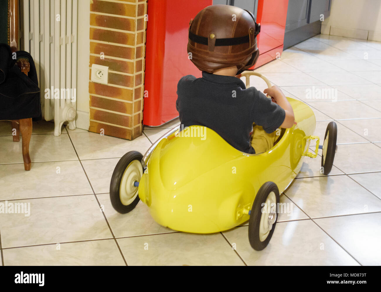 Rear view of little boy riding toy car at home Stock Photo - Alamy
