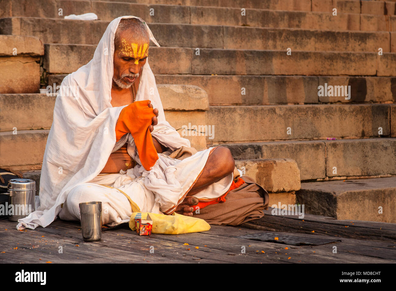A Hindu man sits in prayer before the Ganges, on the ghats in Varanasi ...