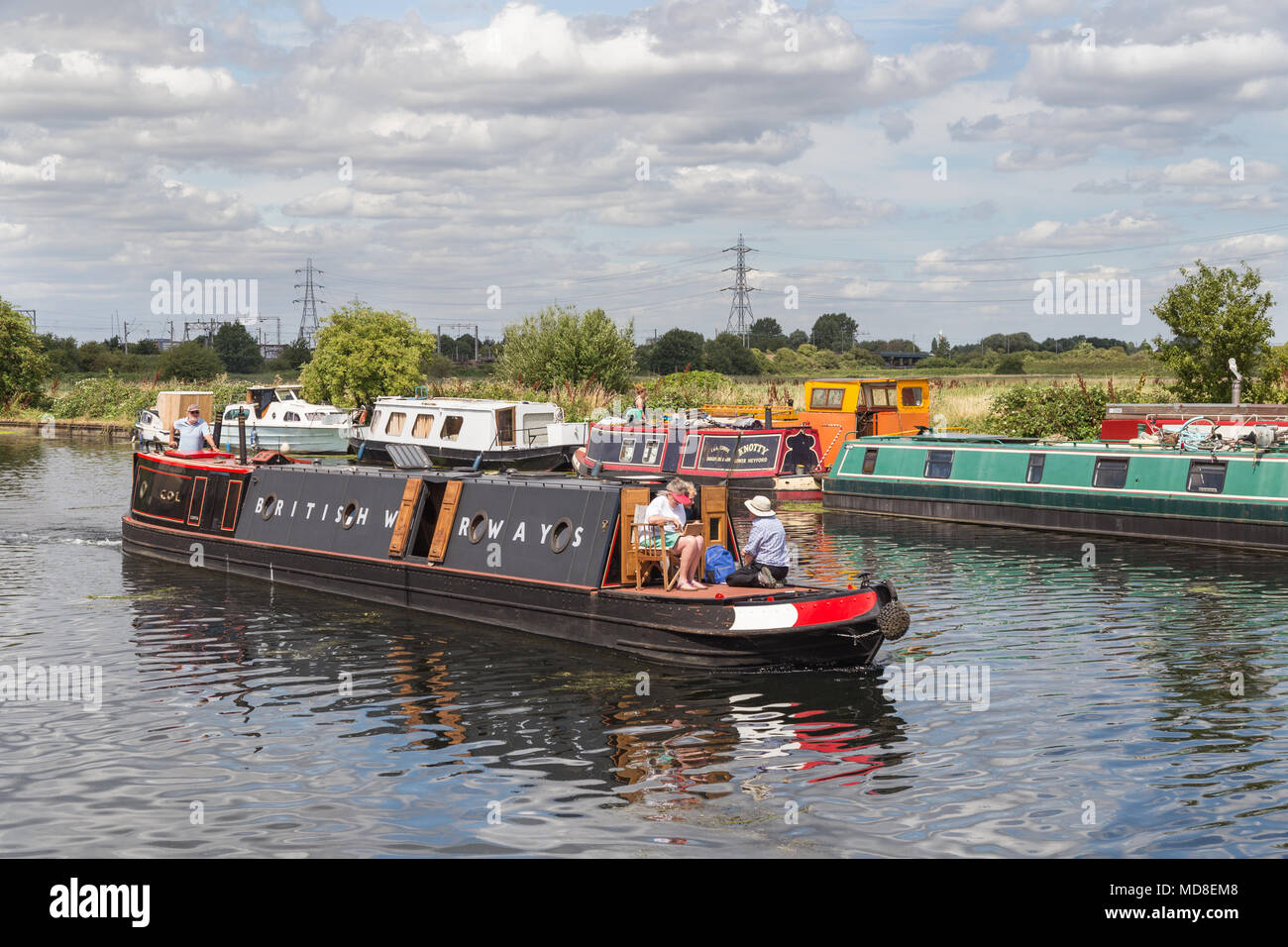 Narrowboat with middle-aged occupants moving along the River Lea in ...