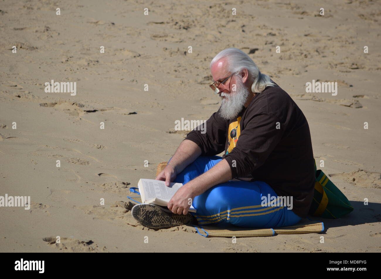 A man reading a book on the bank of the River Thames at Southbank ...