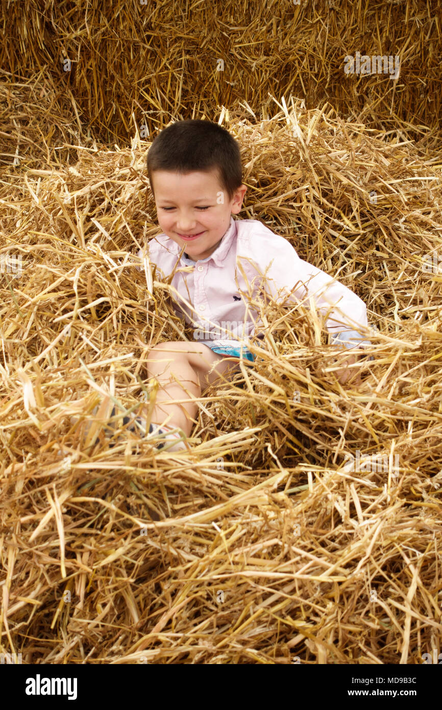 Boy lying and playing on haystack Stock Photo - Alamy