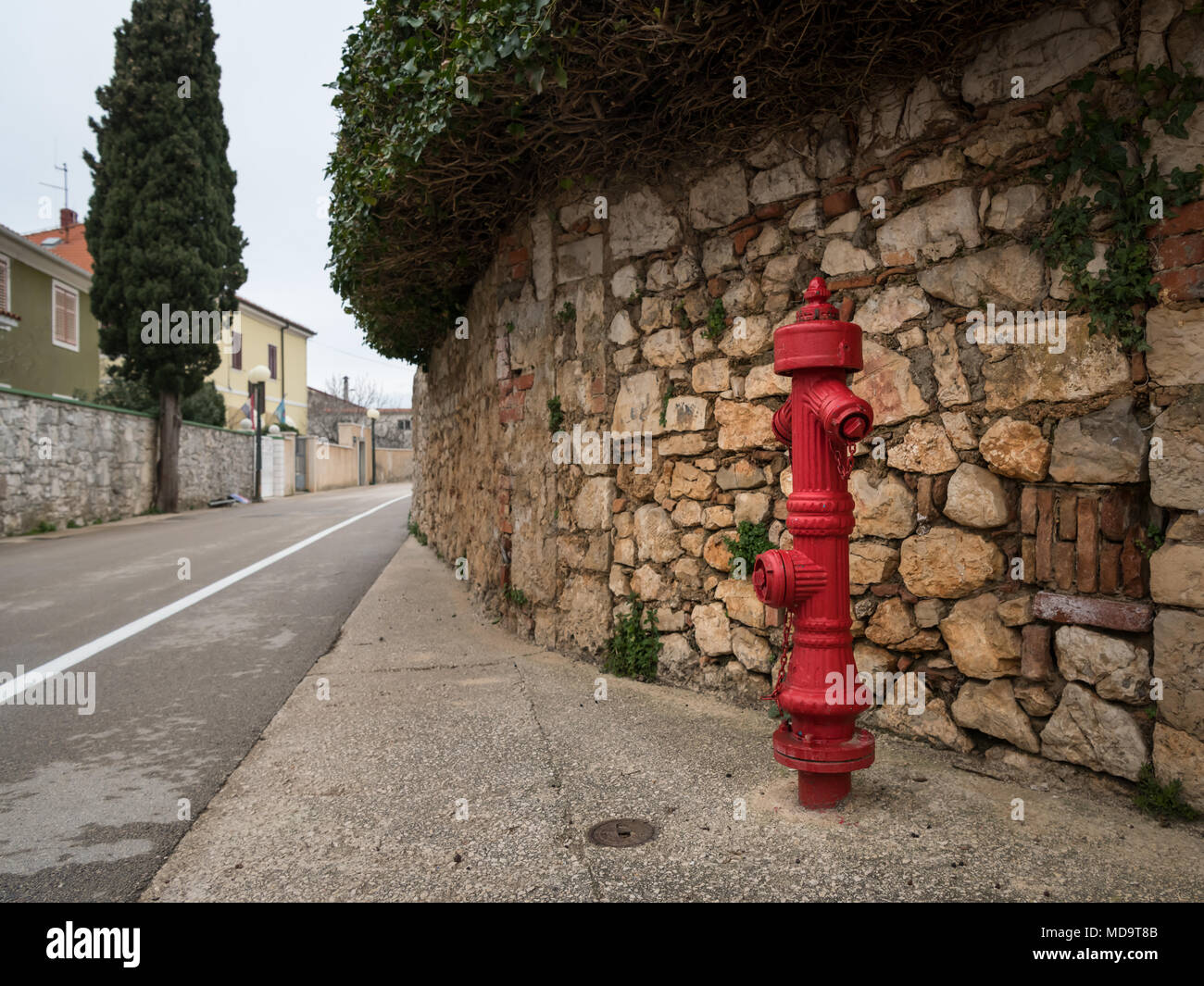 Red fire hydrant in front of a stone wall, Cres Croatia Stock Photo - Alamy
