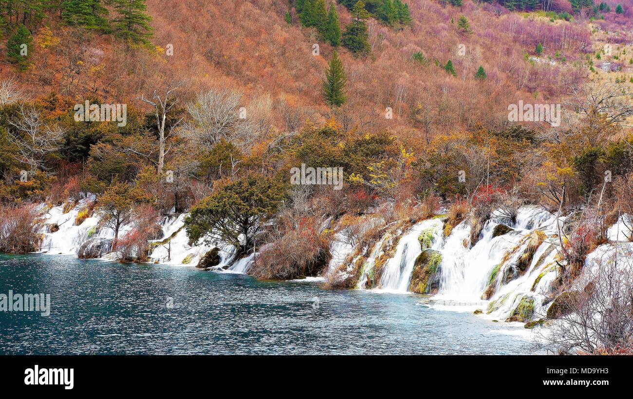 Beautiful waterfall and azure lake with crystal clear water among fall ...
