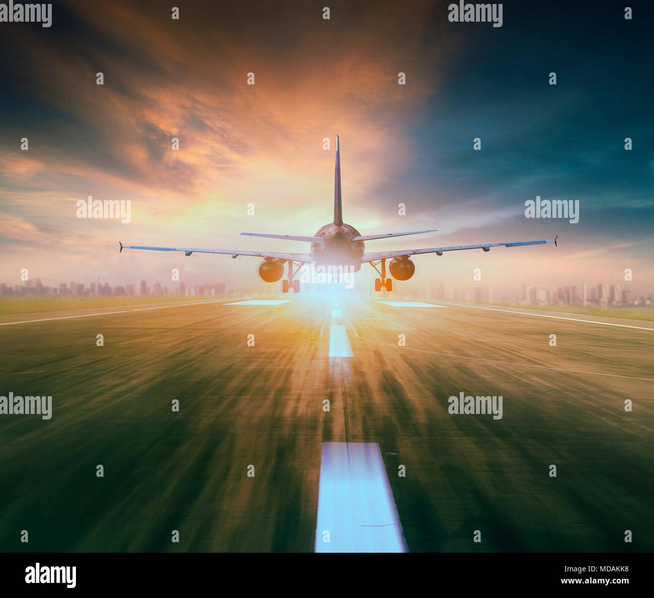air plane flying over airport runway with city scape and sunset sky ...