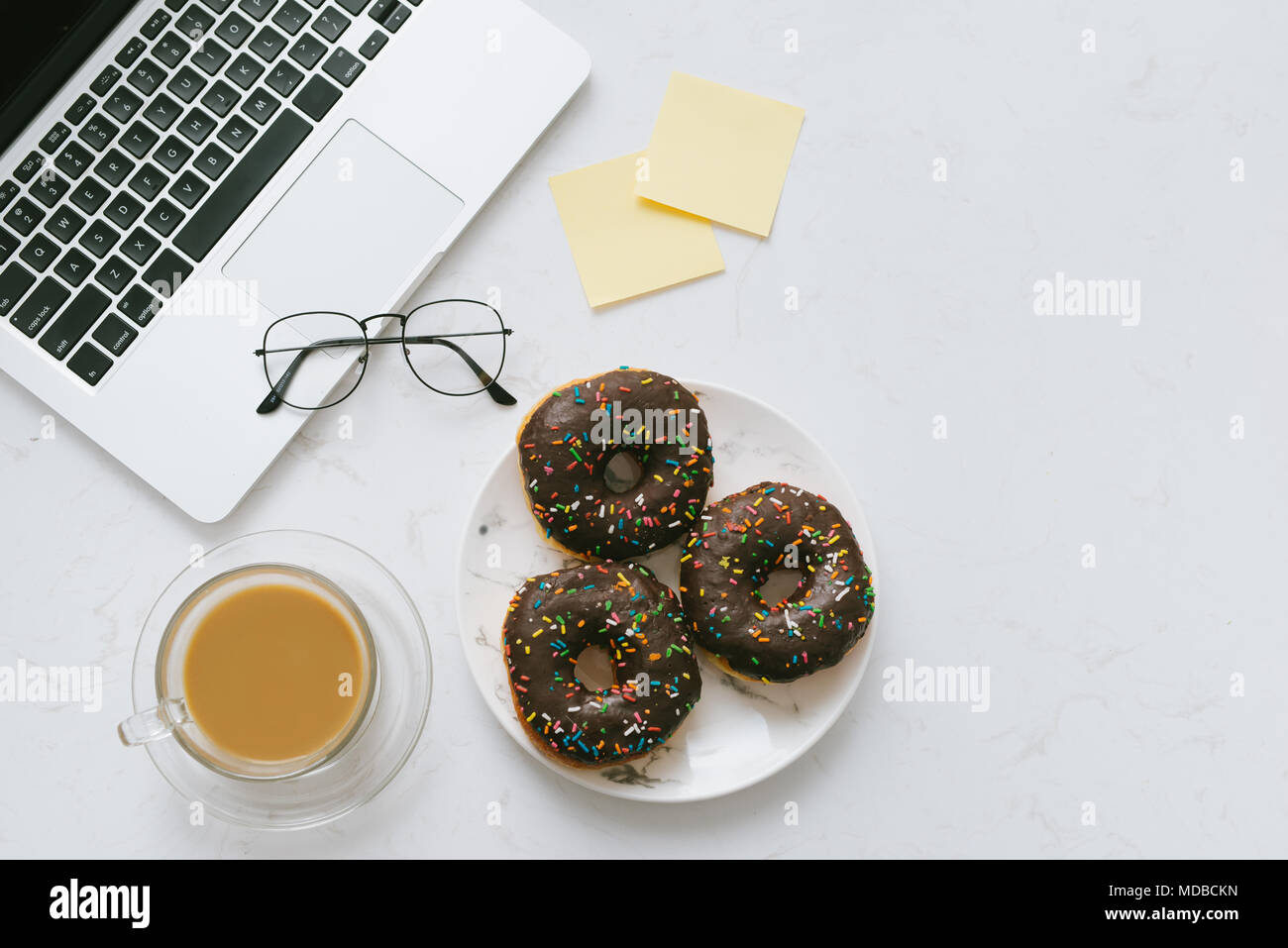 Food in the office. Donuts on working desk Stock Photo - Alamy