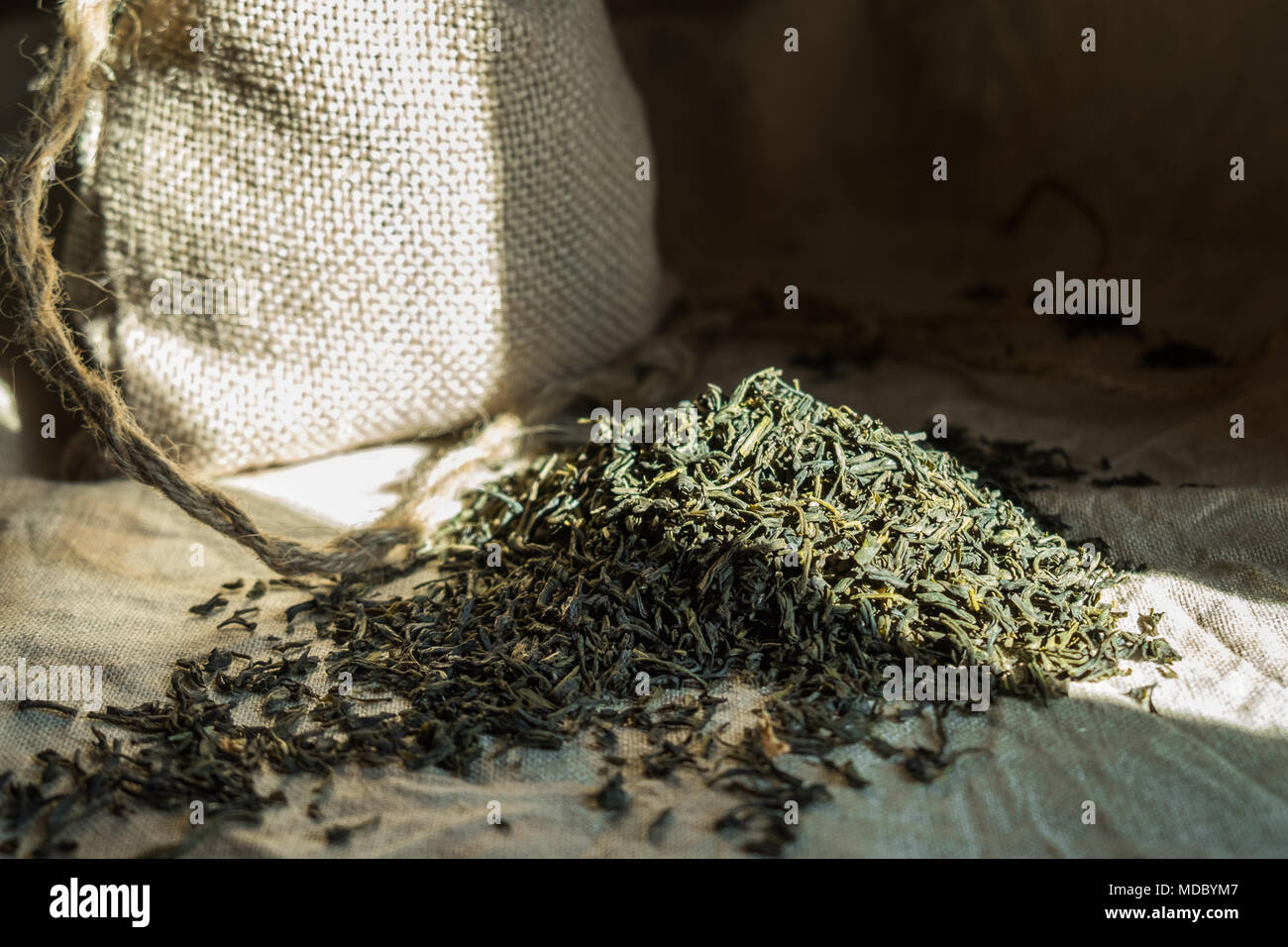 Chinese green tea. Heap of tea leaves on textured linen tablecloth ...