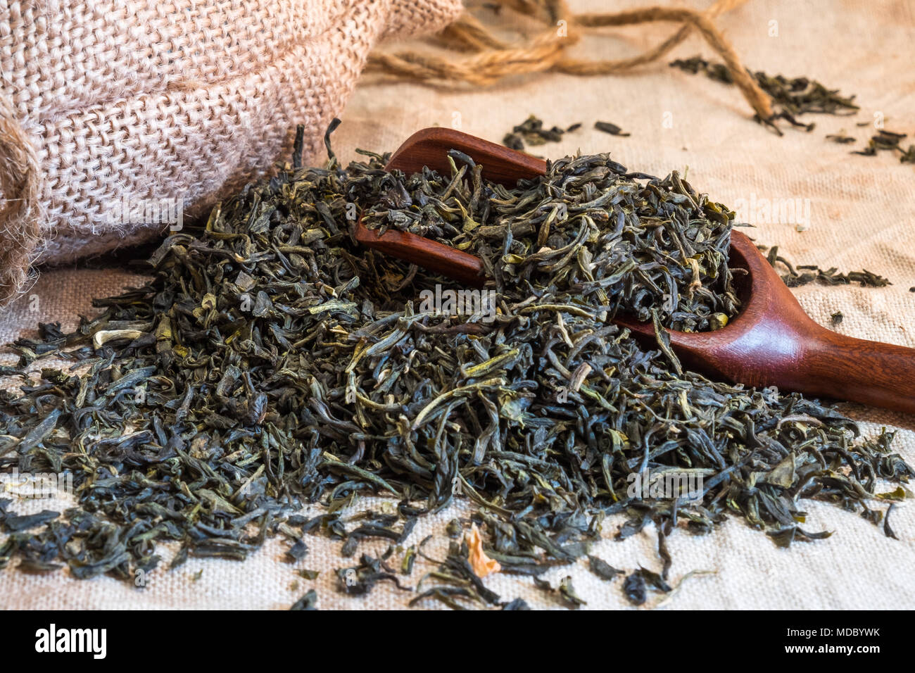Chinese green tea. Heap of tea leaves on textured linen tablecloth with ...
