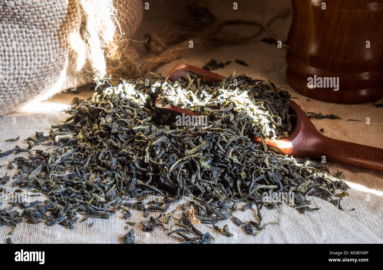 Chinese green tea. Heap of tea leaves on textured linen tablecloth with ...