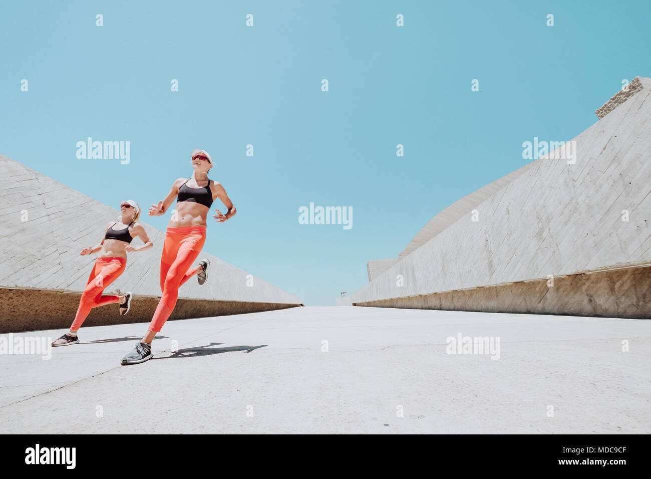 Two female runners running side by side Stock Photo - Alamy