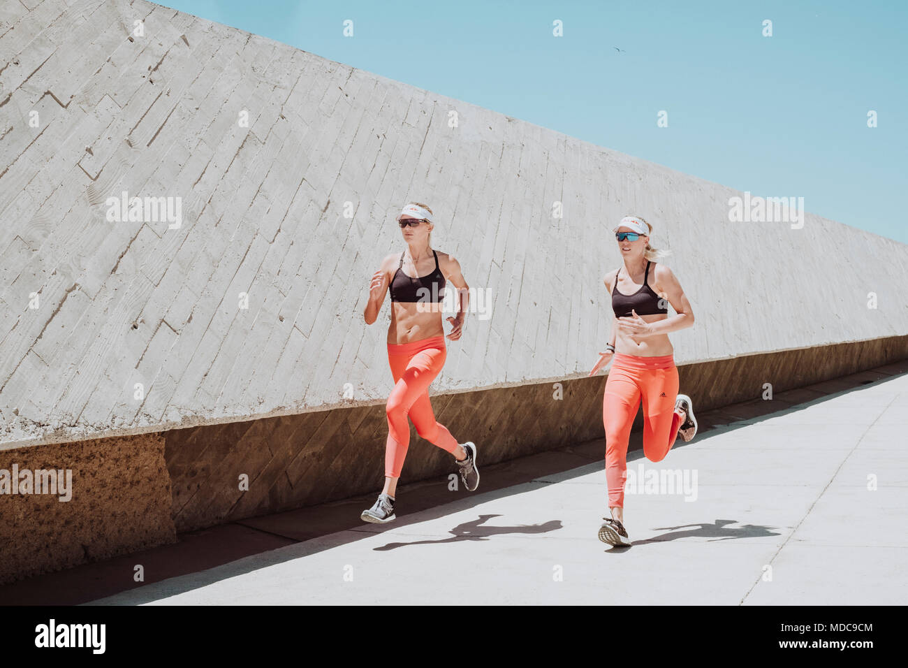 Two female runners running side by side Stock Photo - Alamy