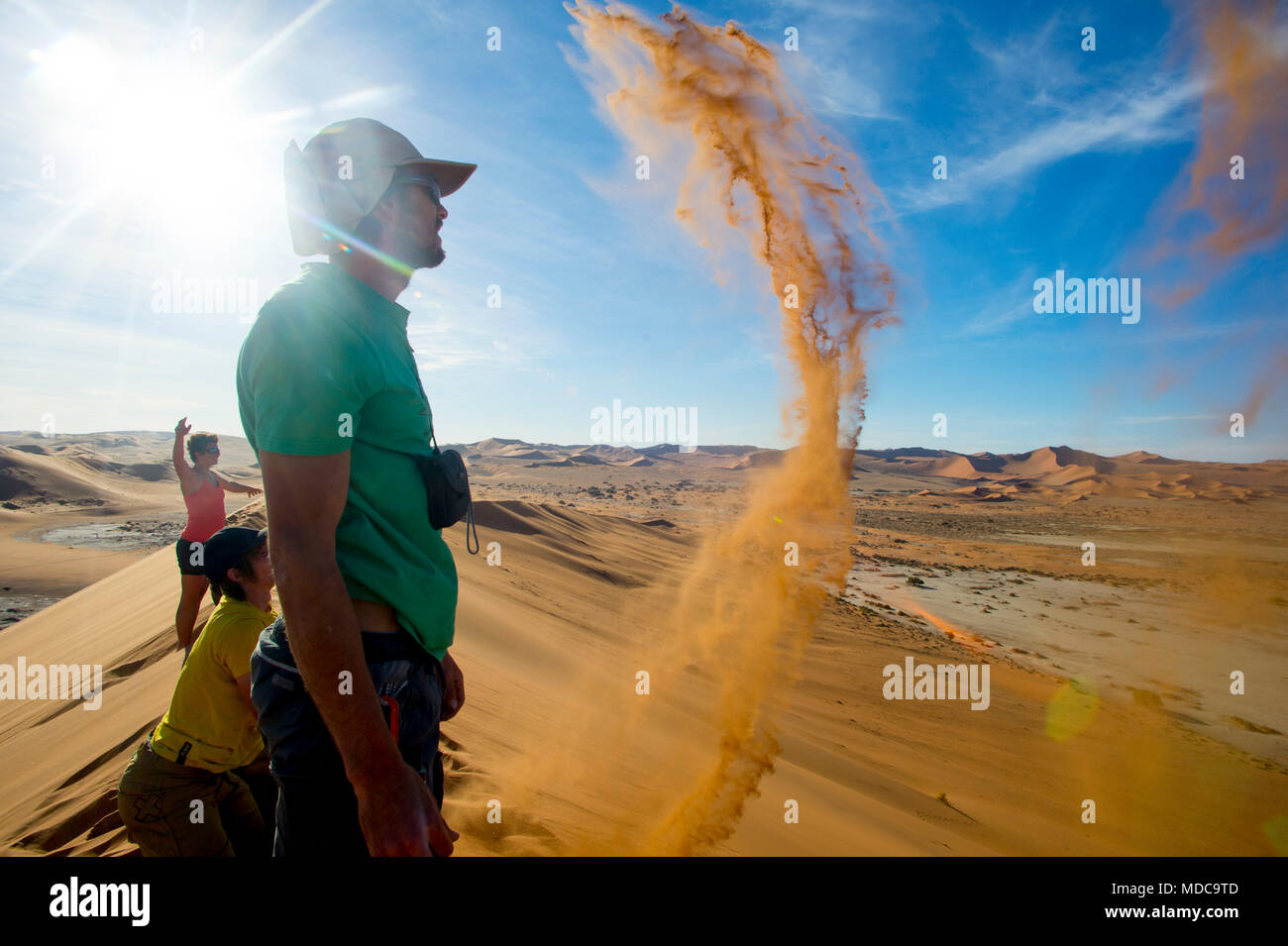 Group of people throwing sand into air in desert, Sossusvlei, Namib ...