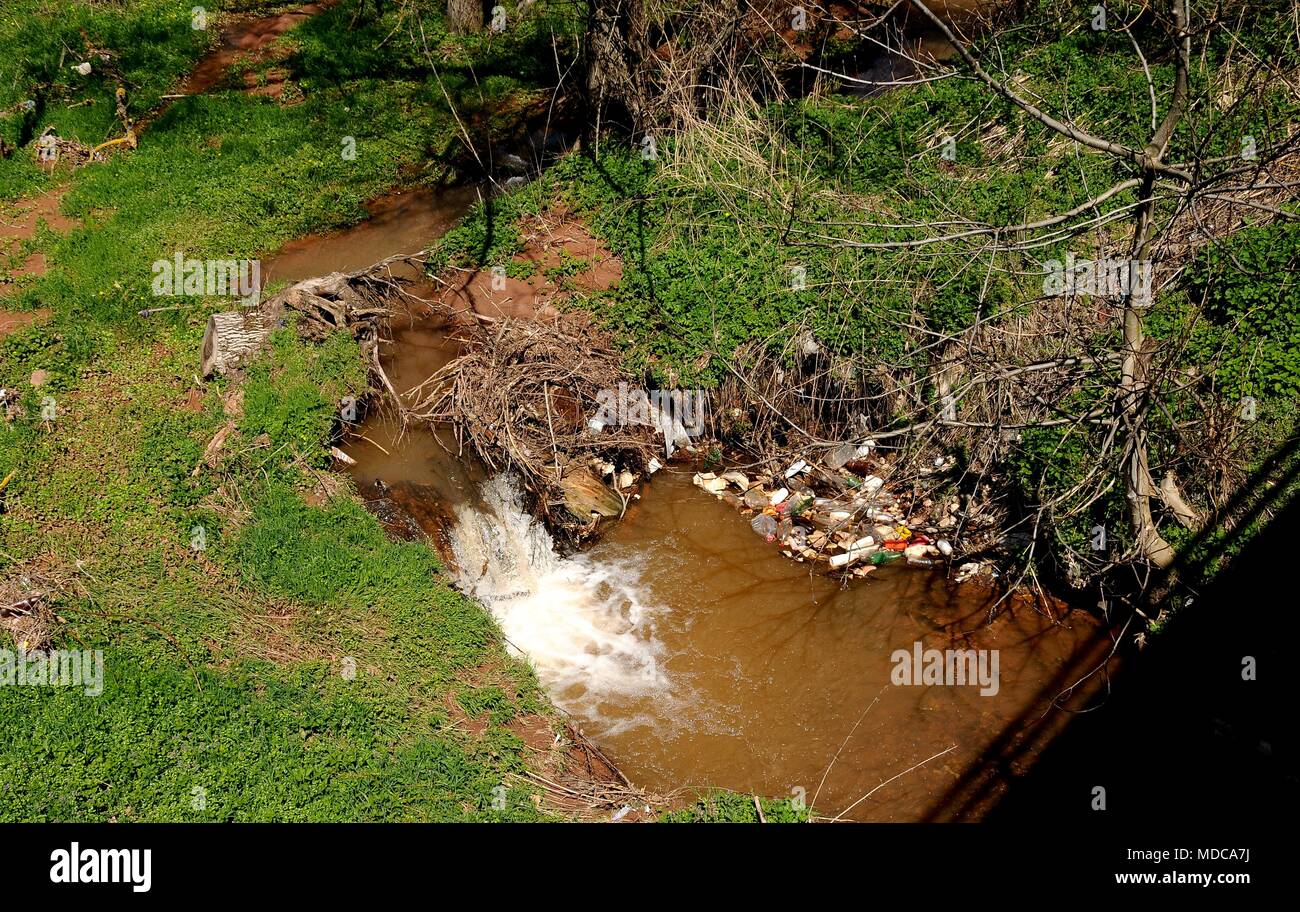 beautiful little river with foliage and plastic bottles and garbage ...