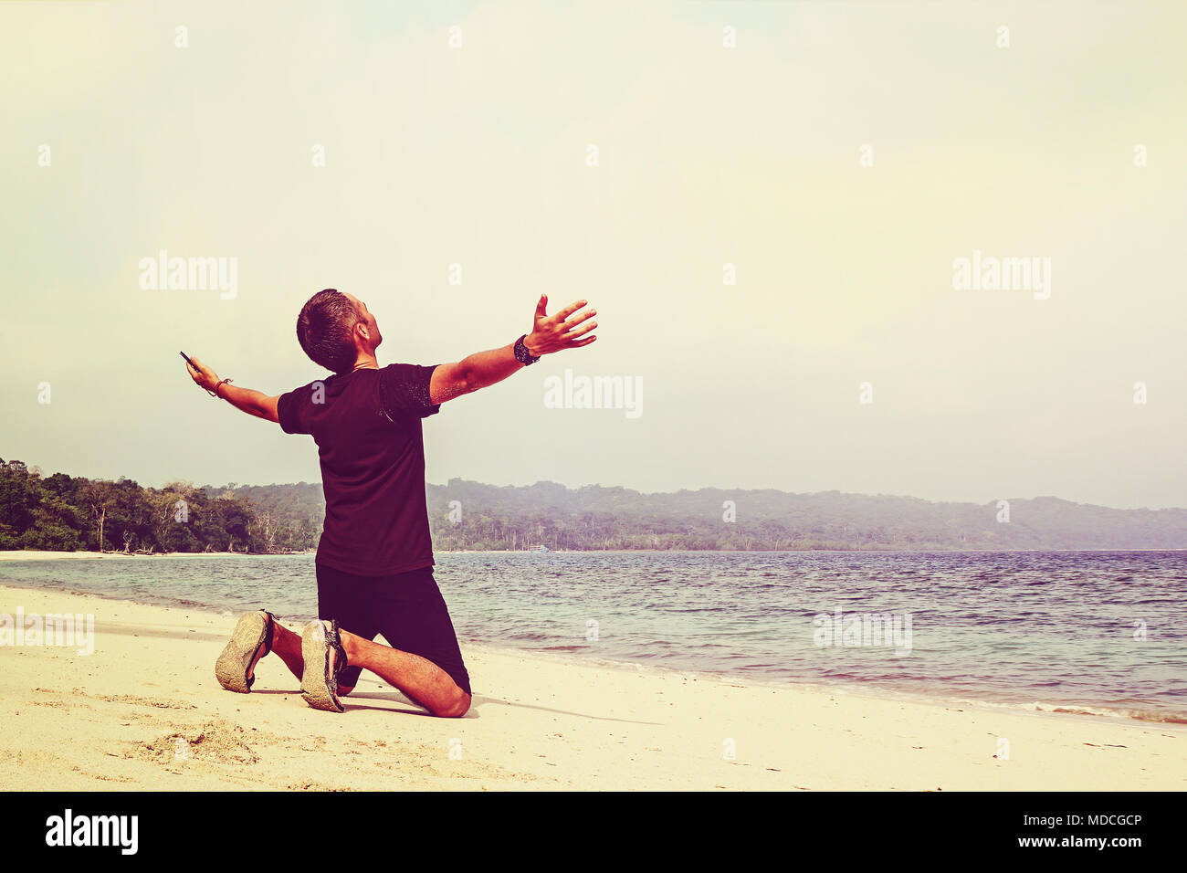 happy young man on the tropical white sand tropical beach rising up ...