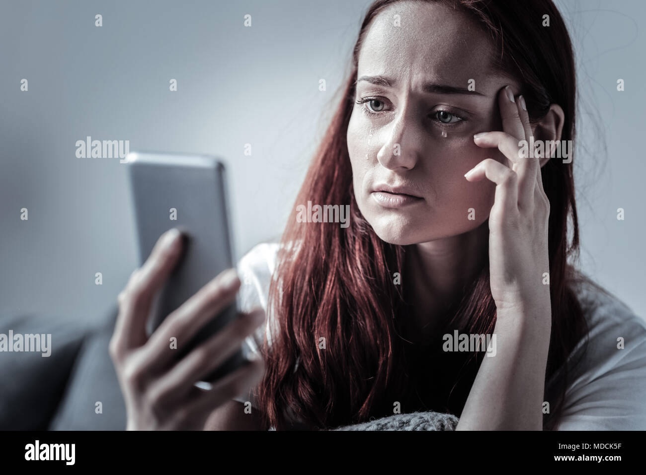 Sorrowful deplorable woman using phone Stock Photo - Alamy