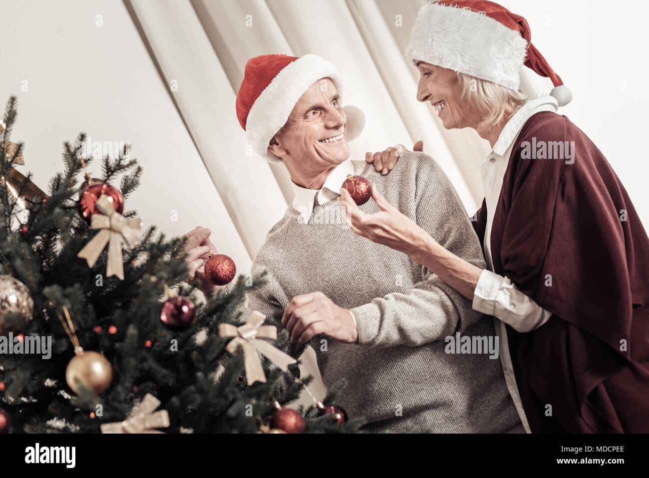 Positive delighted people standing near Christmas tree Stock Photo - Alamy