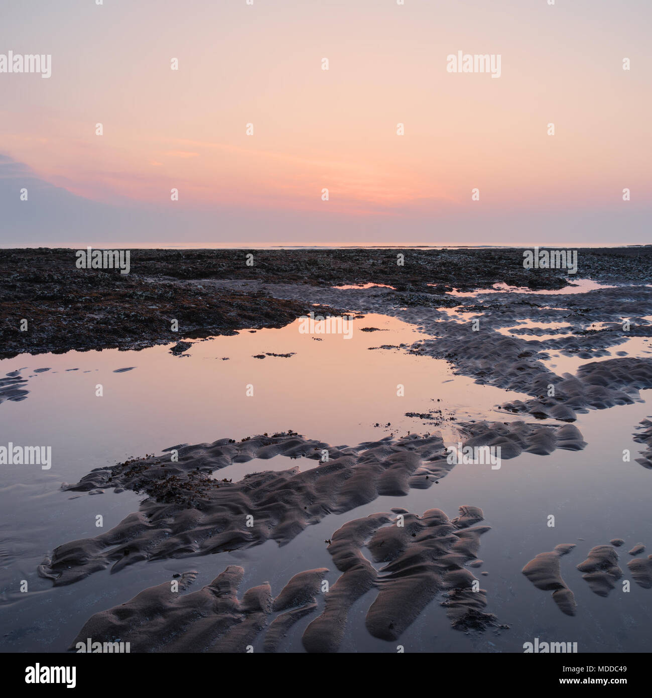 Beautiful vibrant sunrise reflected in rock pools at low tide on beach ...
