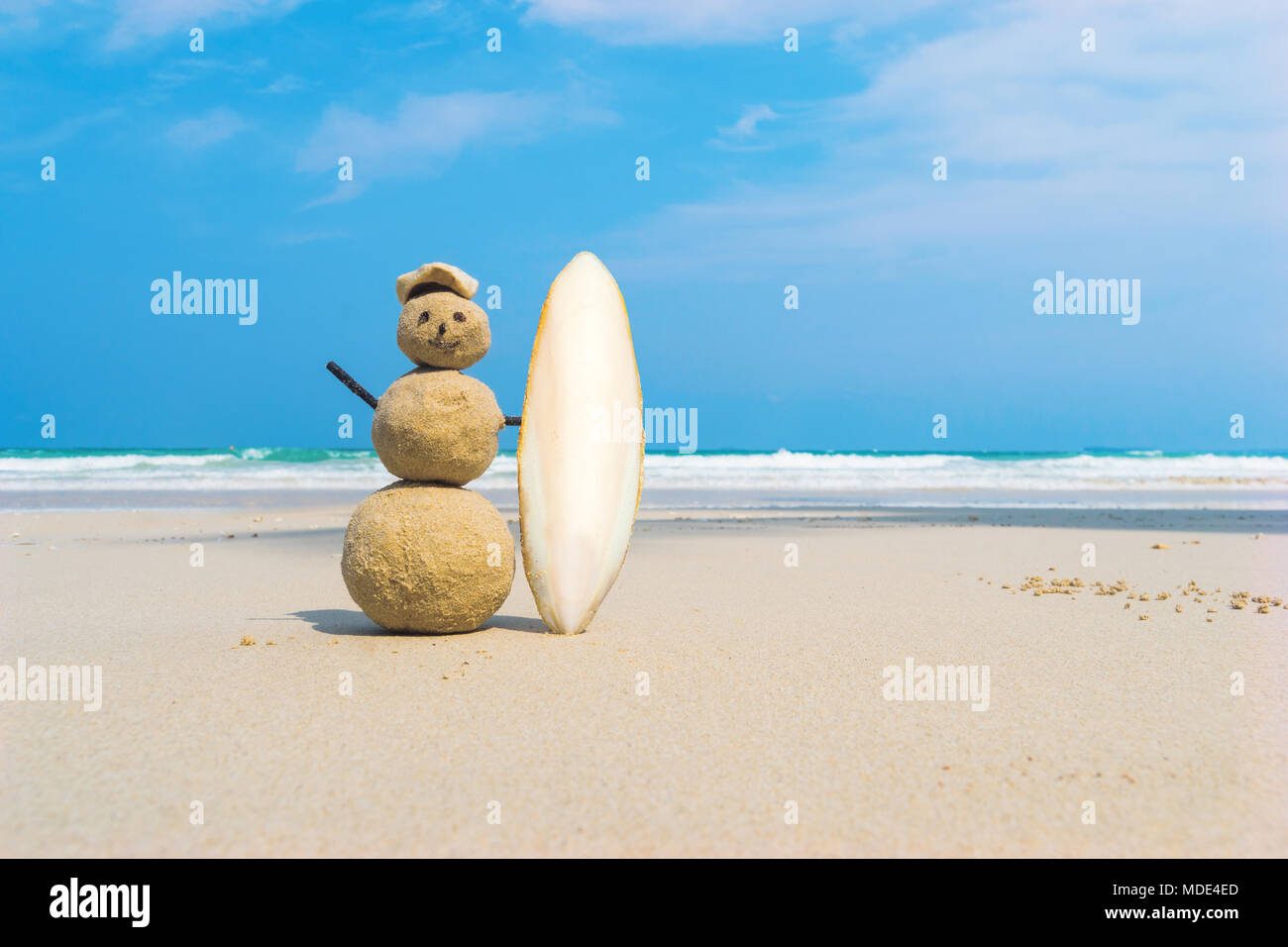Sandman with blue sea background. Handmade yellow sand surfer holding a ...