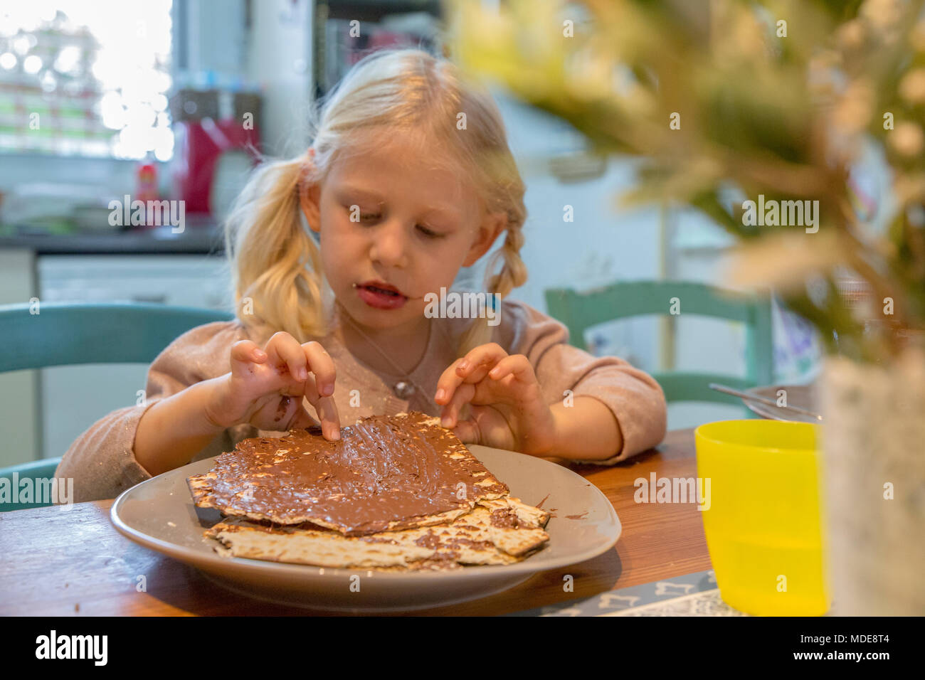 Portrait of a young girl of five eats Matzo with chocolate spread ...