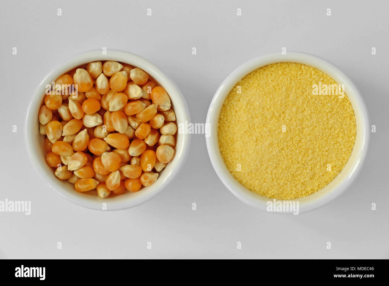 Dry corn kernels and corn flour in bowl on white background Stock Photo ...