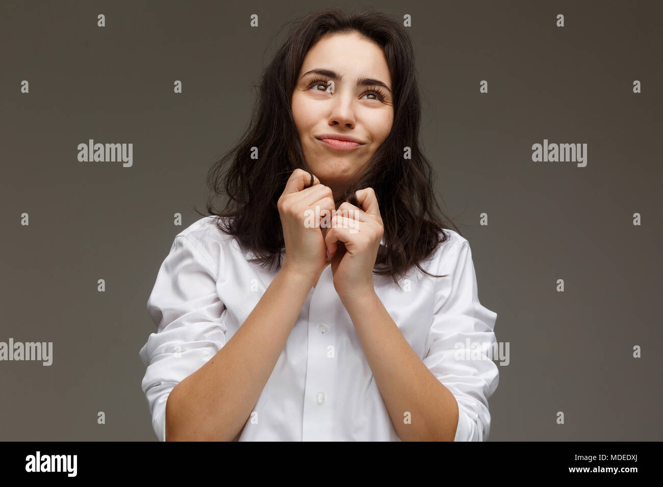 Beautiful girl in a white shirt shows emotions - smile, fun. On a light ...