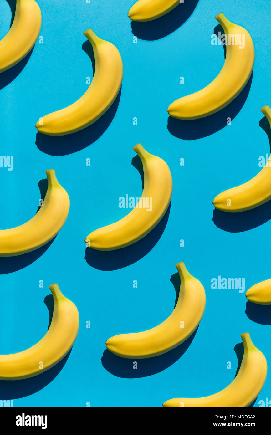 Seamless backdrop of colorful yellow bananas composed on blue surface ...