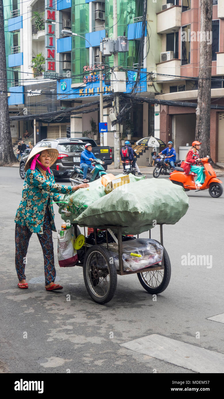 A Vietnamese woman pushing a handcart loaded with green bags on the ...