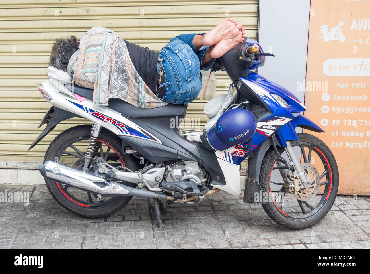 A man sleeping while balanced on a motorcycle in Ho Chi Minh City ...