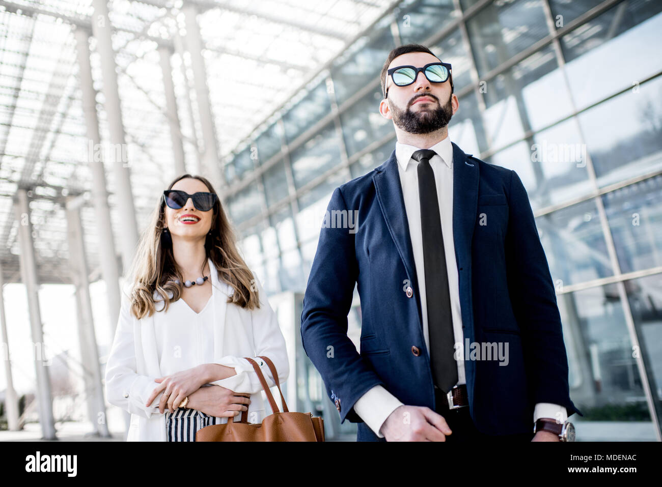 Business woman and man in suits standing near the modern building ...
