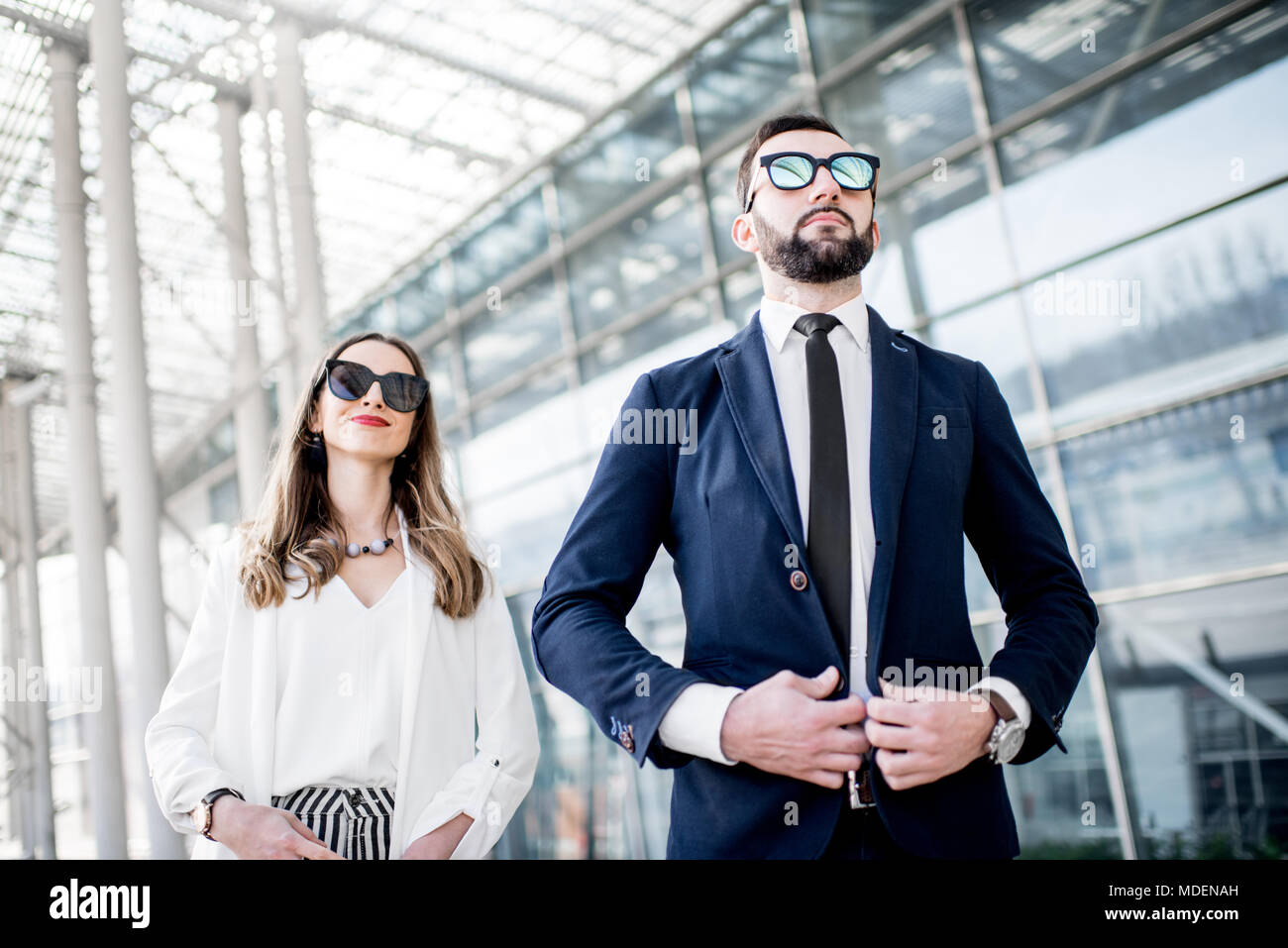 Business woman and man in suits standing near the modern building ...