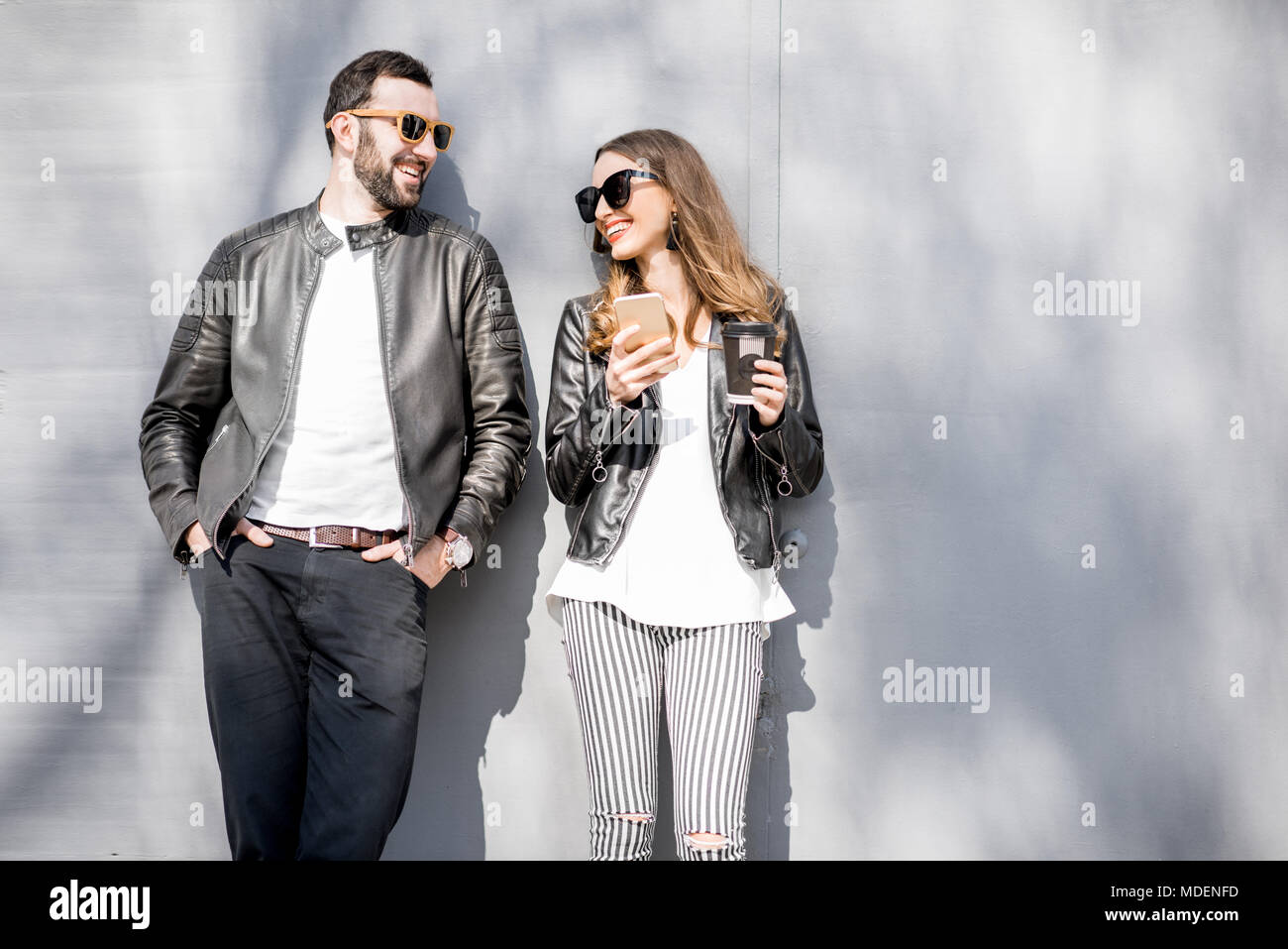 Young stylish couple in leather jackets having fun talking together on ...
