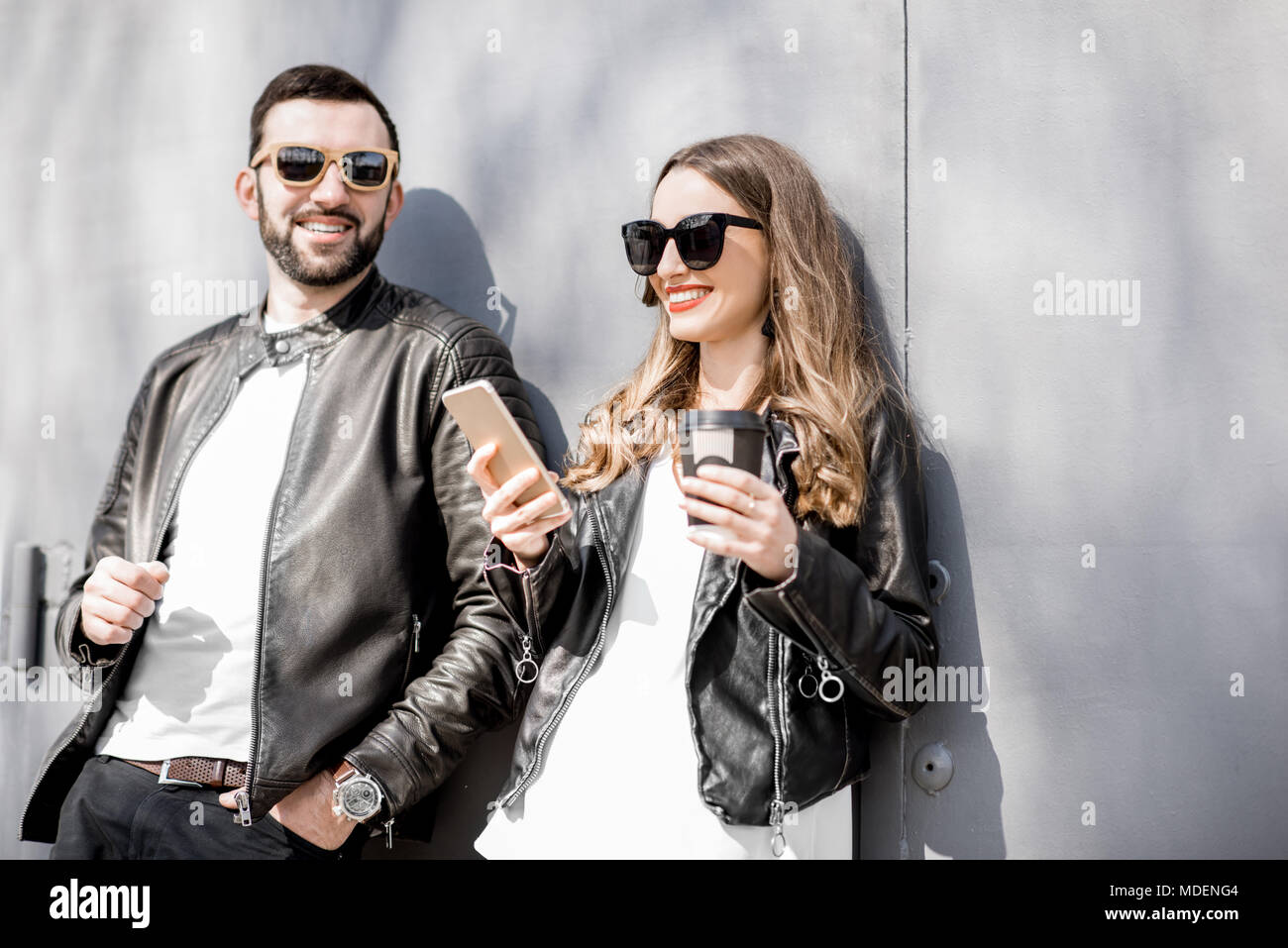 Young stylish couple in leather jackets having fun talking together on ...
