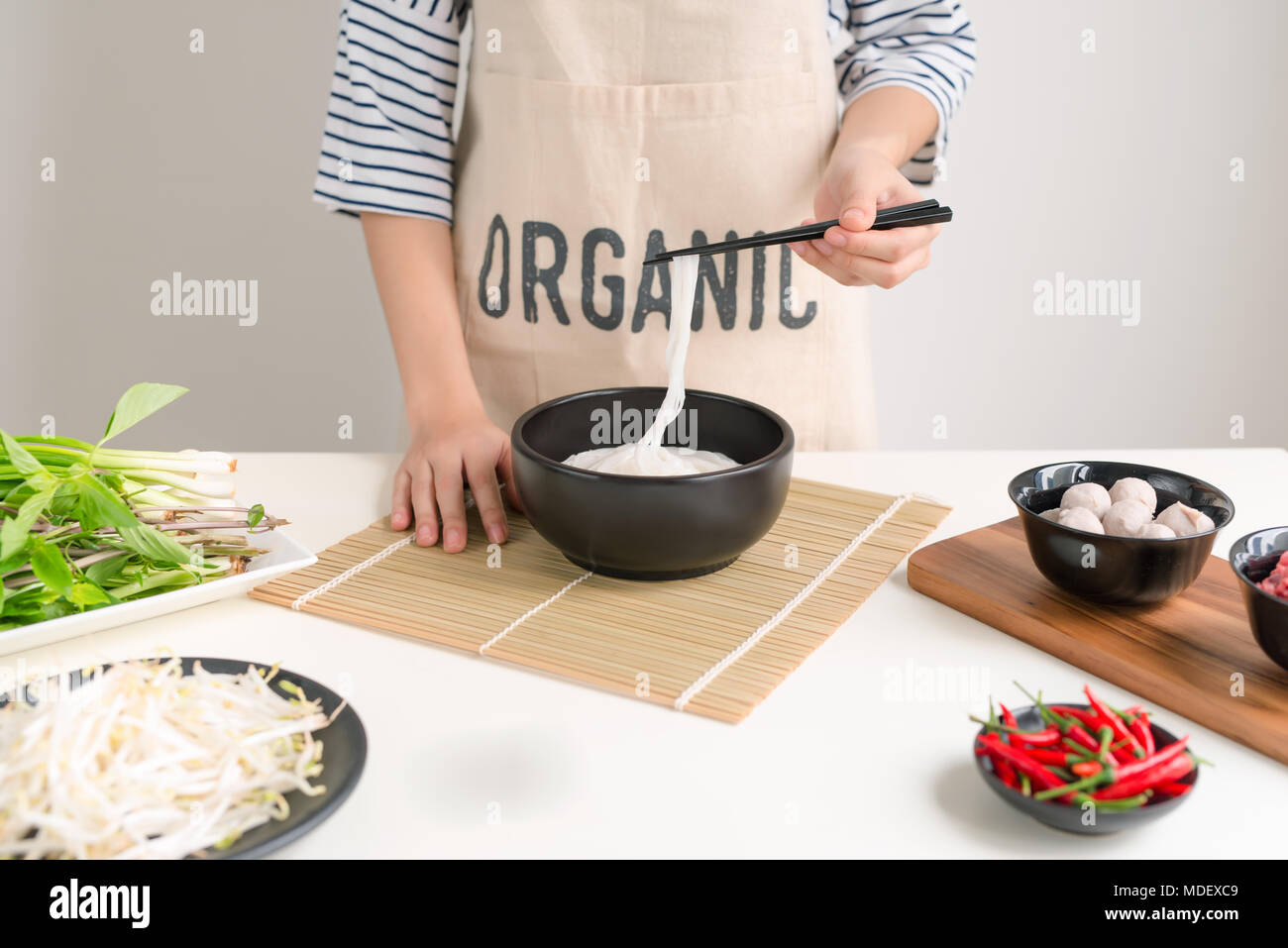 Female chef prepare traditional Vietnamese soup Pho bo with herbs, meat ...