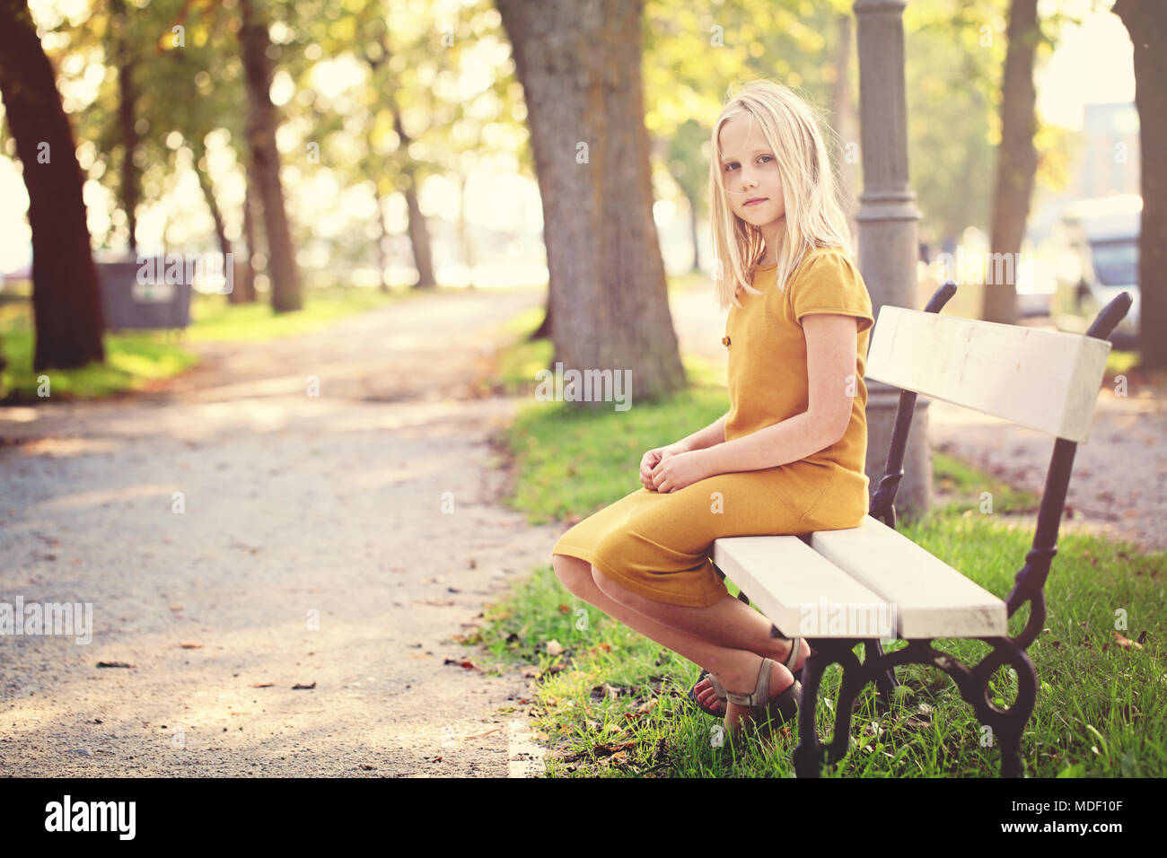 Young Girl Sitting on a Bench Stock Photo - Alamy