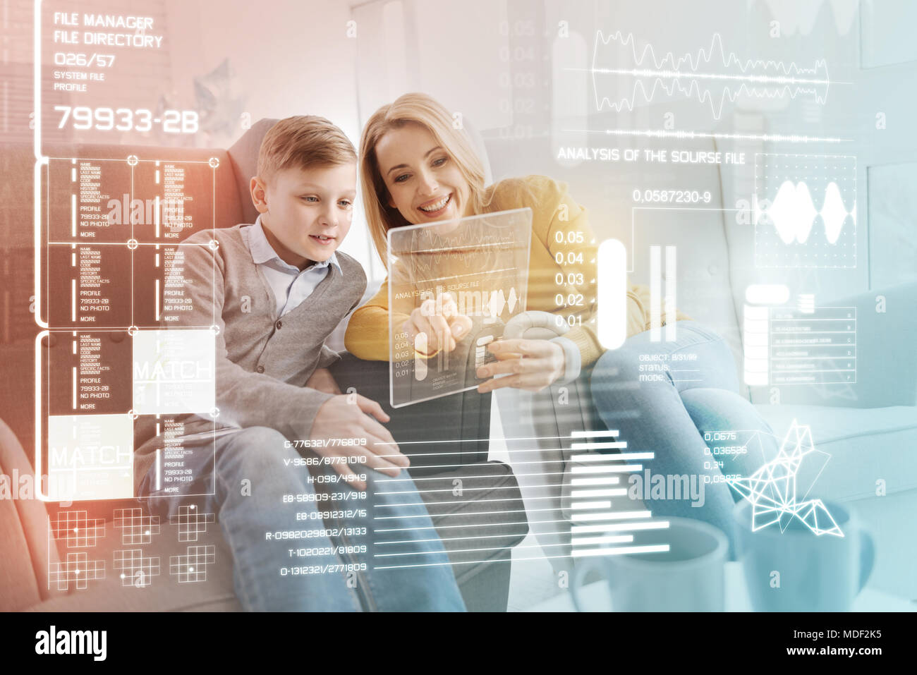 Positive programmer smiling while showing her child a transparent tablet Stock Photo - Alamy