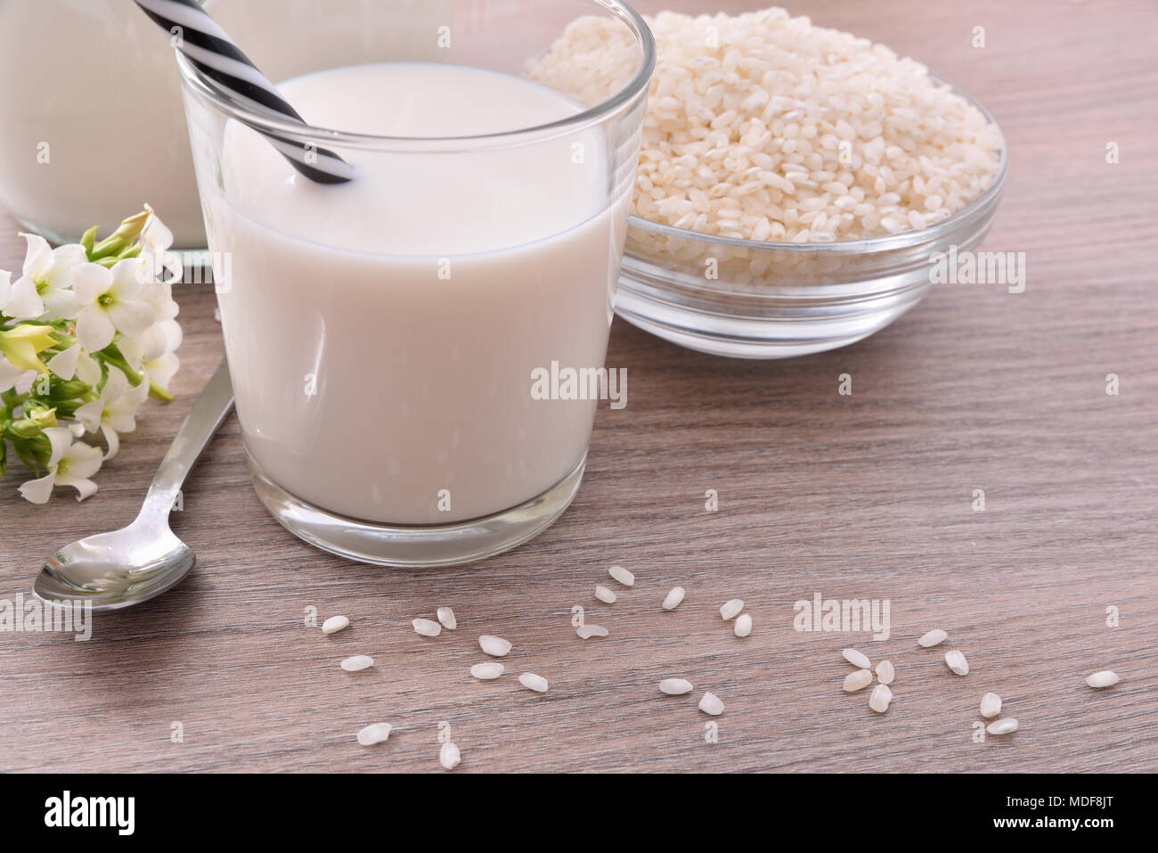 Rice milk and rice in containers on a wooden table in rustic kitchen ...